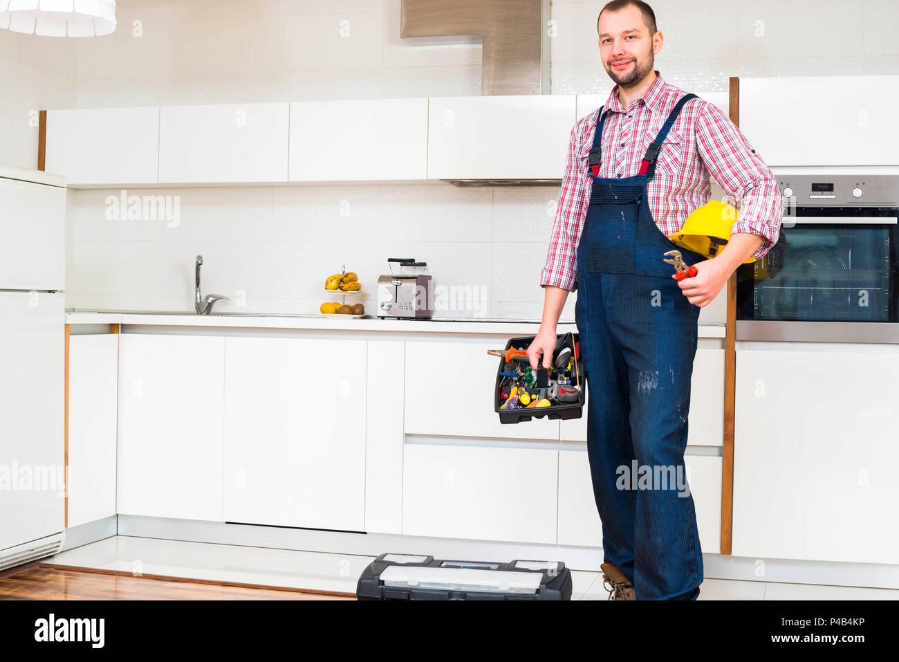 Standing guy holding his toolbox and helmet in the kitchen Stock Photo ...