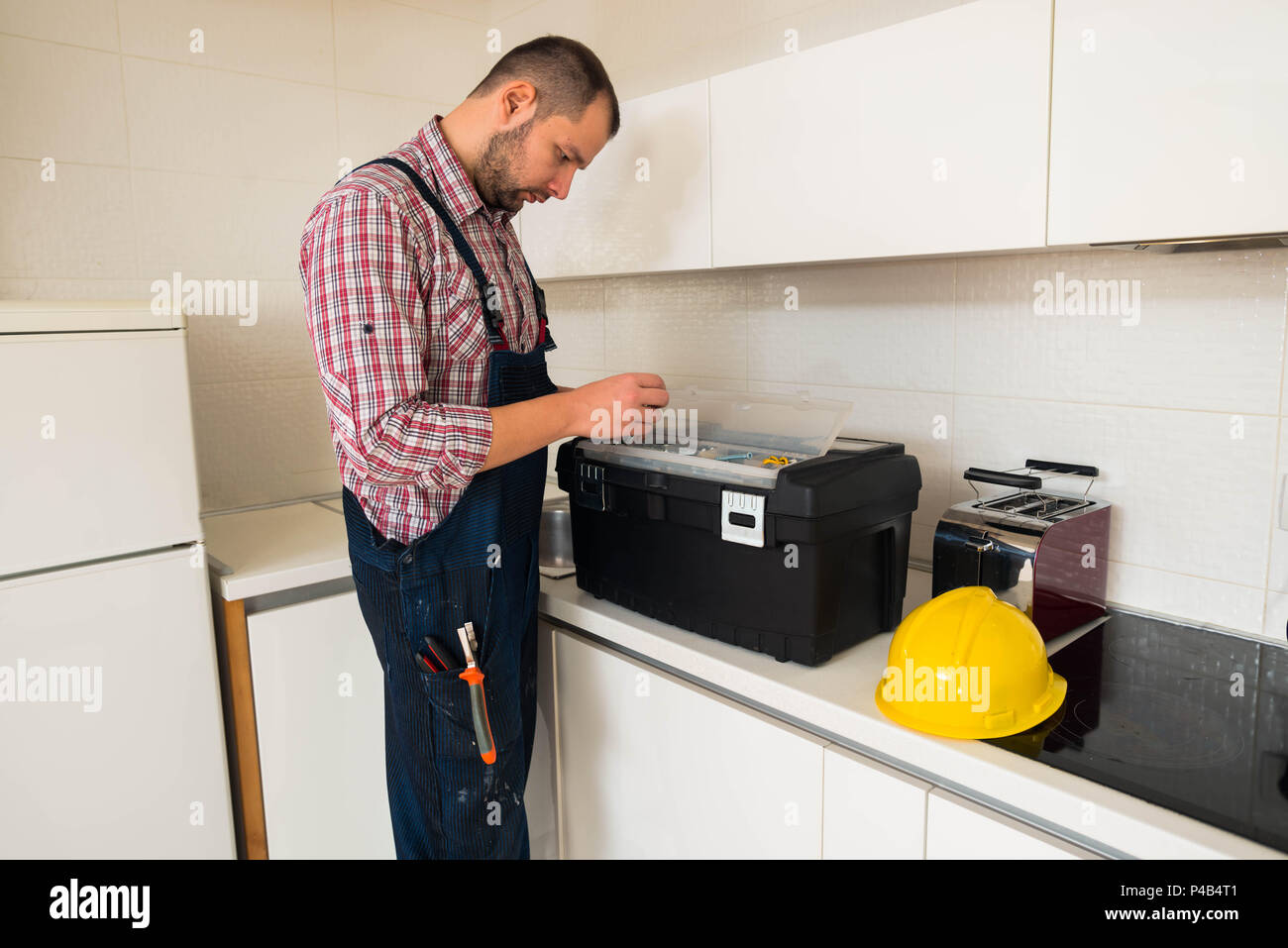 Repairman searching his tool in kitchen Stock Photo - Alamy