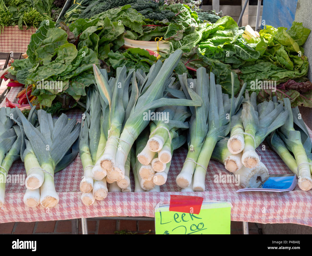 Leek vegetables sitting on table for sale at an outdoor farmers market ...