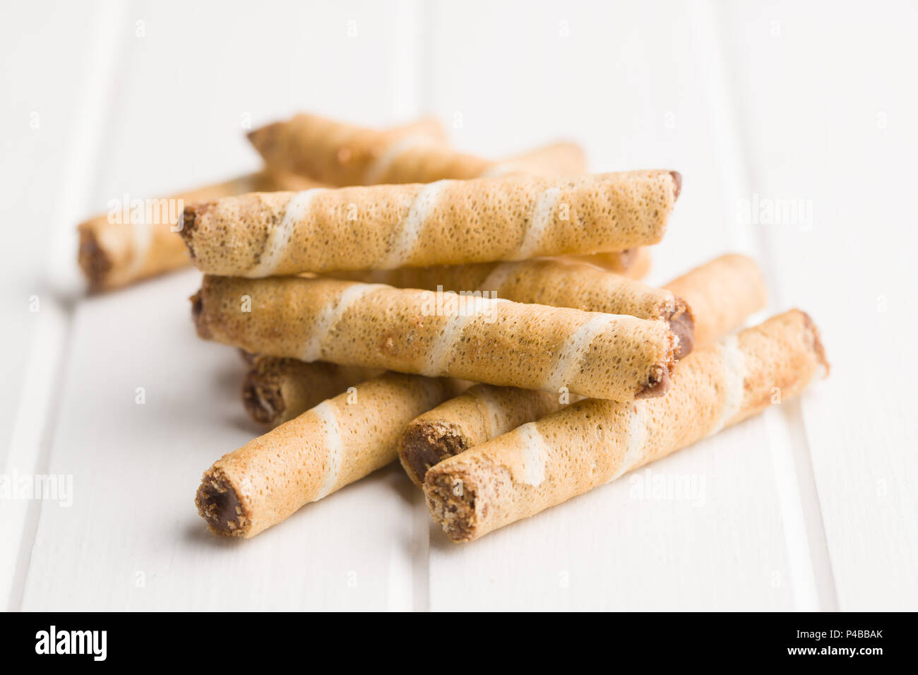 Sweet chocolate waffle rolls on white table Stock Photo - Alamy