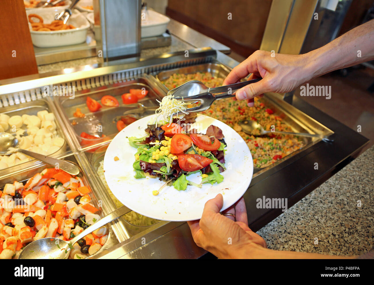 customer of a self-service restaurant serving himself from trays with ...