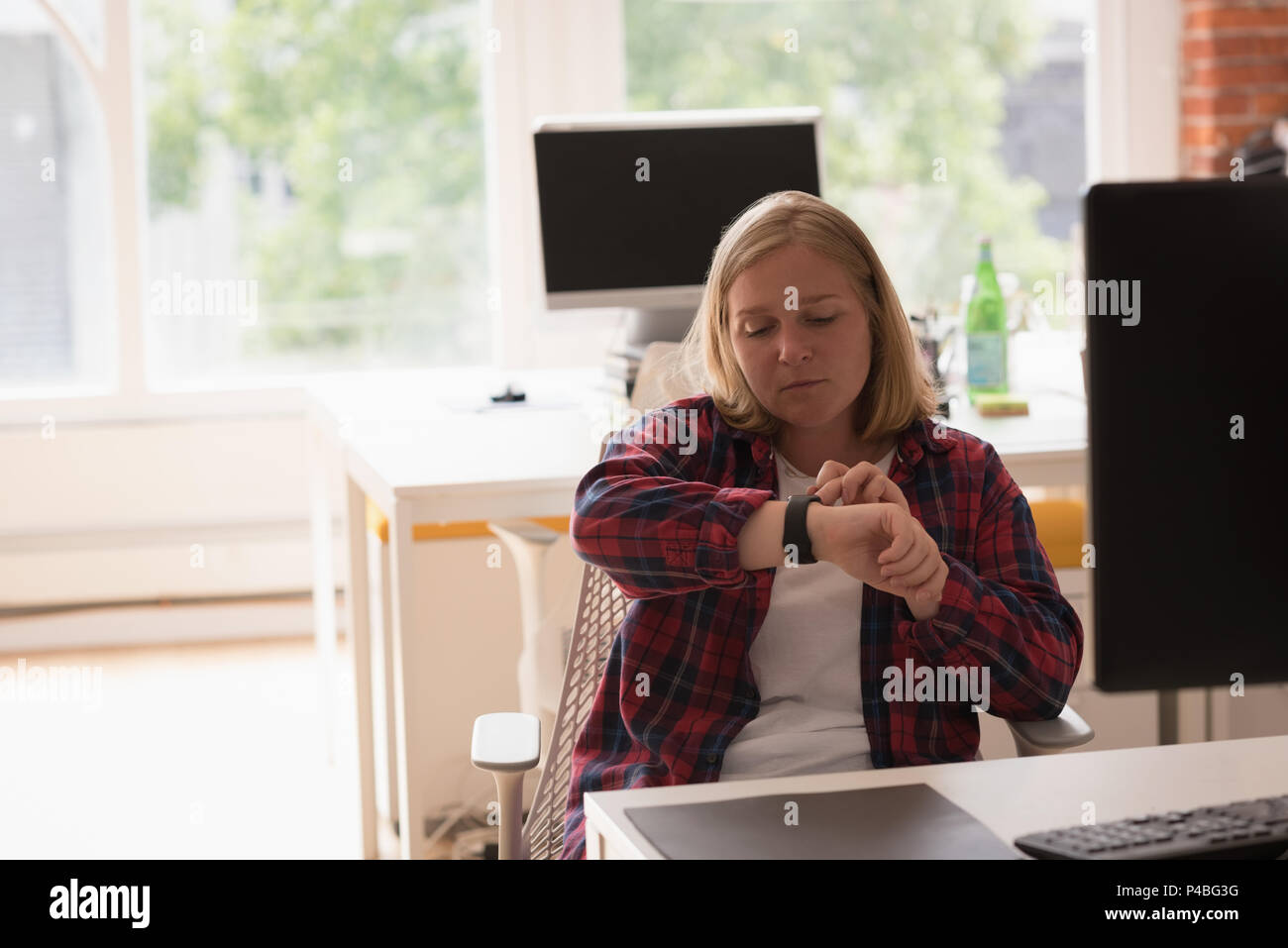 Female executive checking time on her smart watch Stock Photo - Alamy