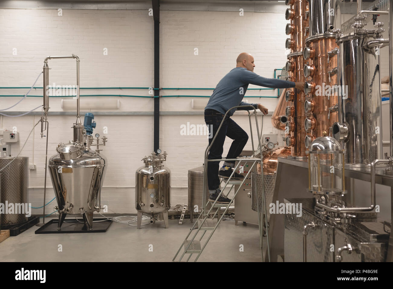 Male worker checking machine of distillery Stock Photo - Alamy