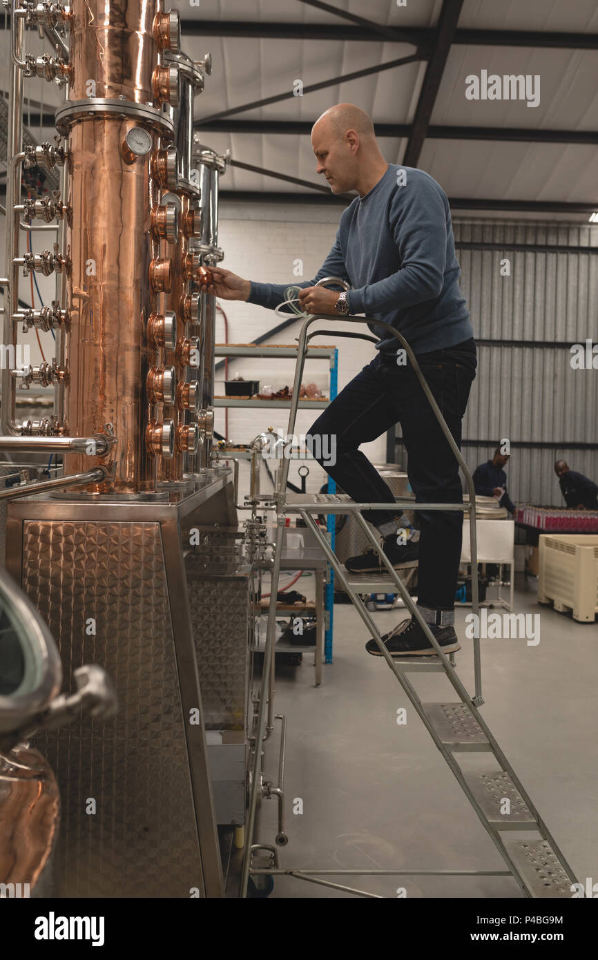 Male worker checking machine of distillery Stock Photo - Alamy