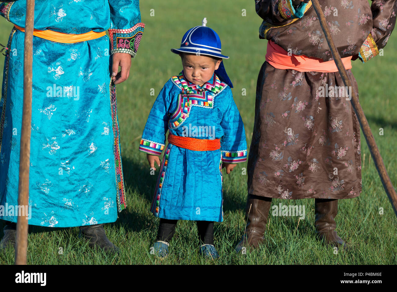 Wearing traditional Mongolian dress, a young boy pridefully stands with ...