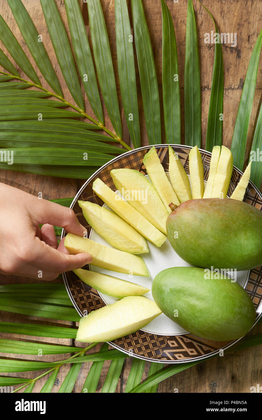 Close-up of hand taking slice of mango above top view Stock Photo - Alamy