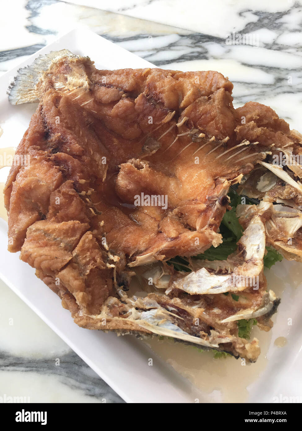 Close up fried snapper fish with fish sauce on white dish in restaurant ...