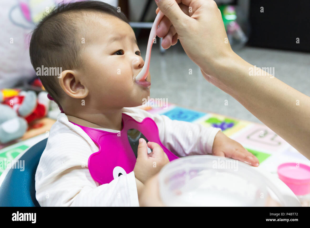 Asian cute baby eating food, Mother feeding first solid food for young ...