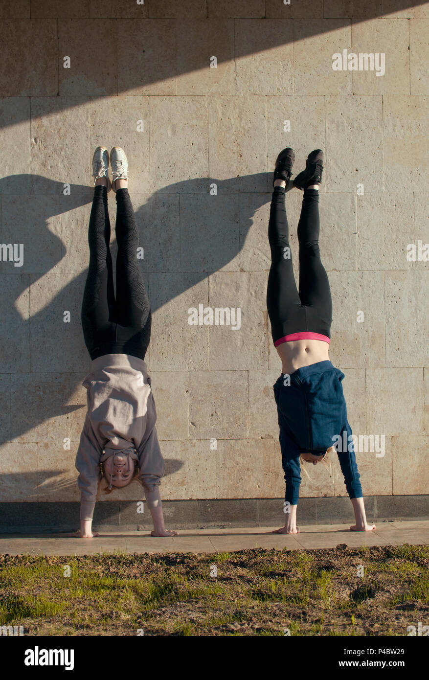 Two young women acrobat doing handstand on the wall with cityscape on ...