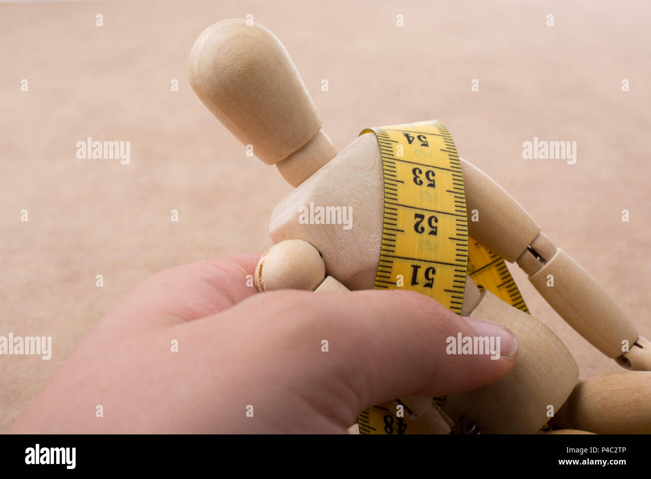 Yellow color measuring tape wrapped on wooden man Stock Photo - Alamy