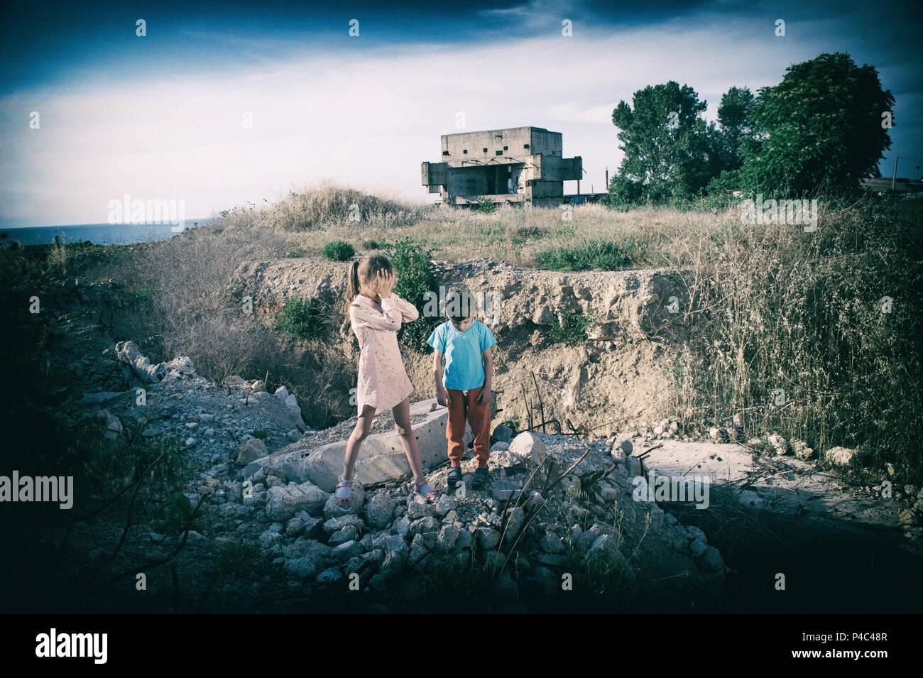 crying caucasian little girl and sad boy on ruins of their house ...