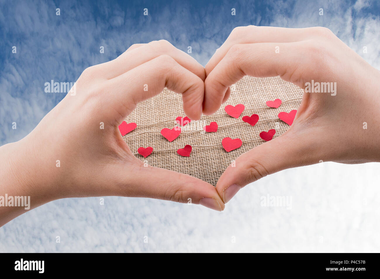 Paper heart shapes behind a heart shaped hand Stock Photo - Alamy