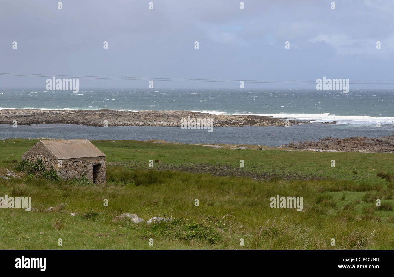 Old stone farm building with waves coming ashore at Fanad Head County ...