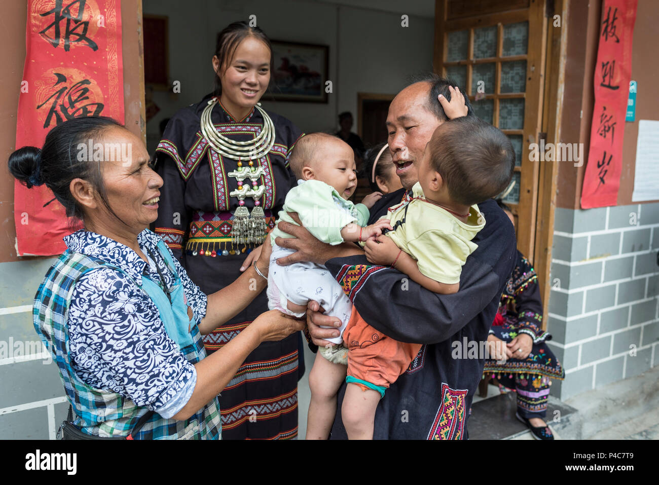 Grandmother, wiggling babies and father dressed in traditional costumes ...
