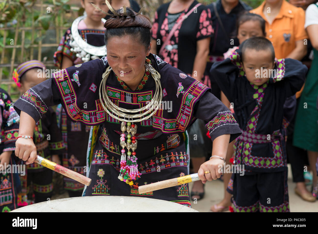 Boy covers ears as woman drums at hunting dance, Yao ethnic minority ...