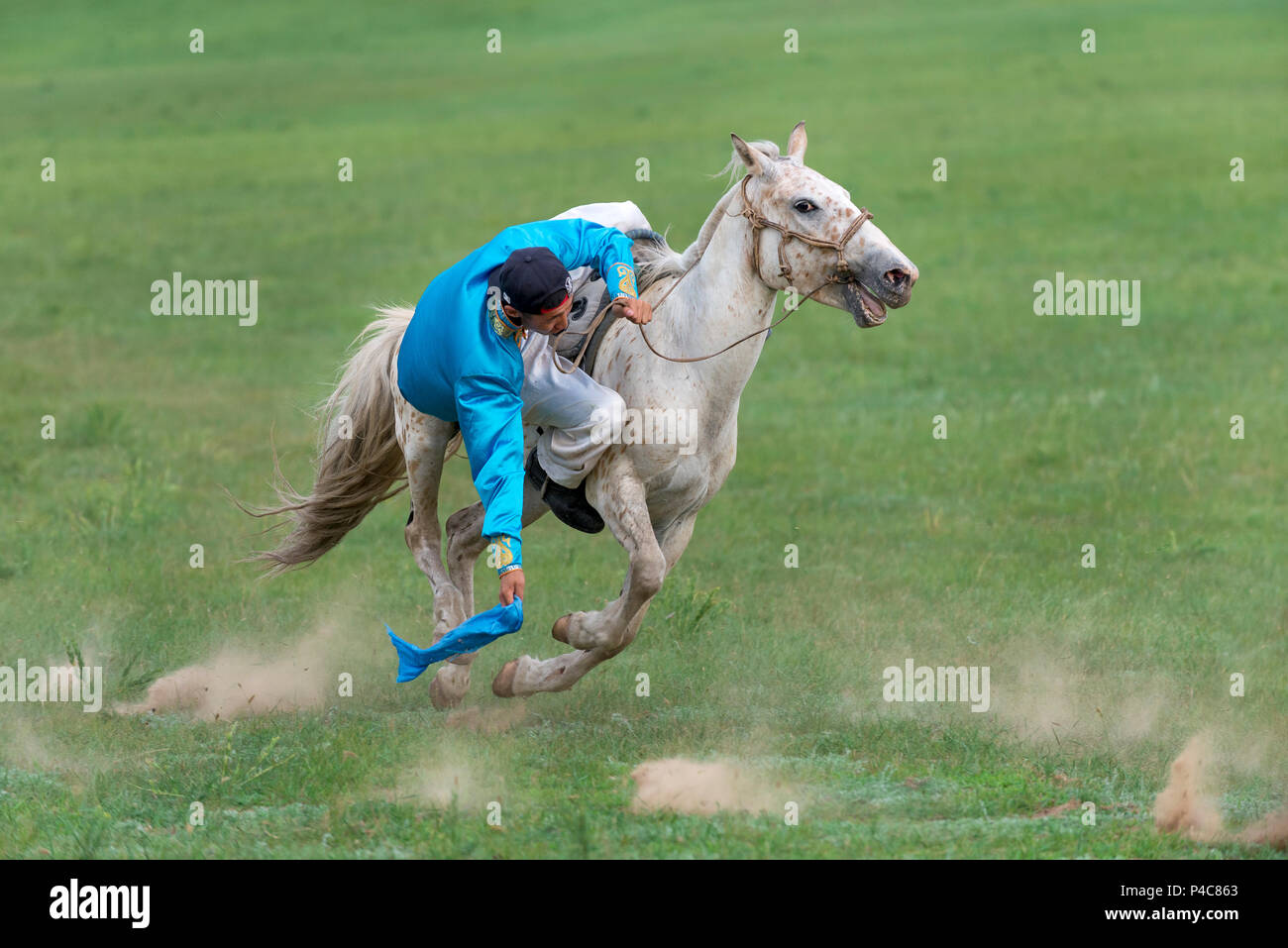 Young horsemen demonstrate riding by picking up scarf from ground ...