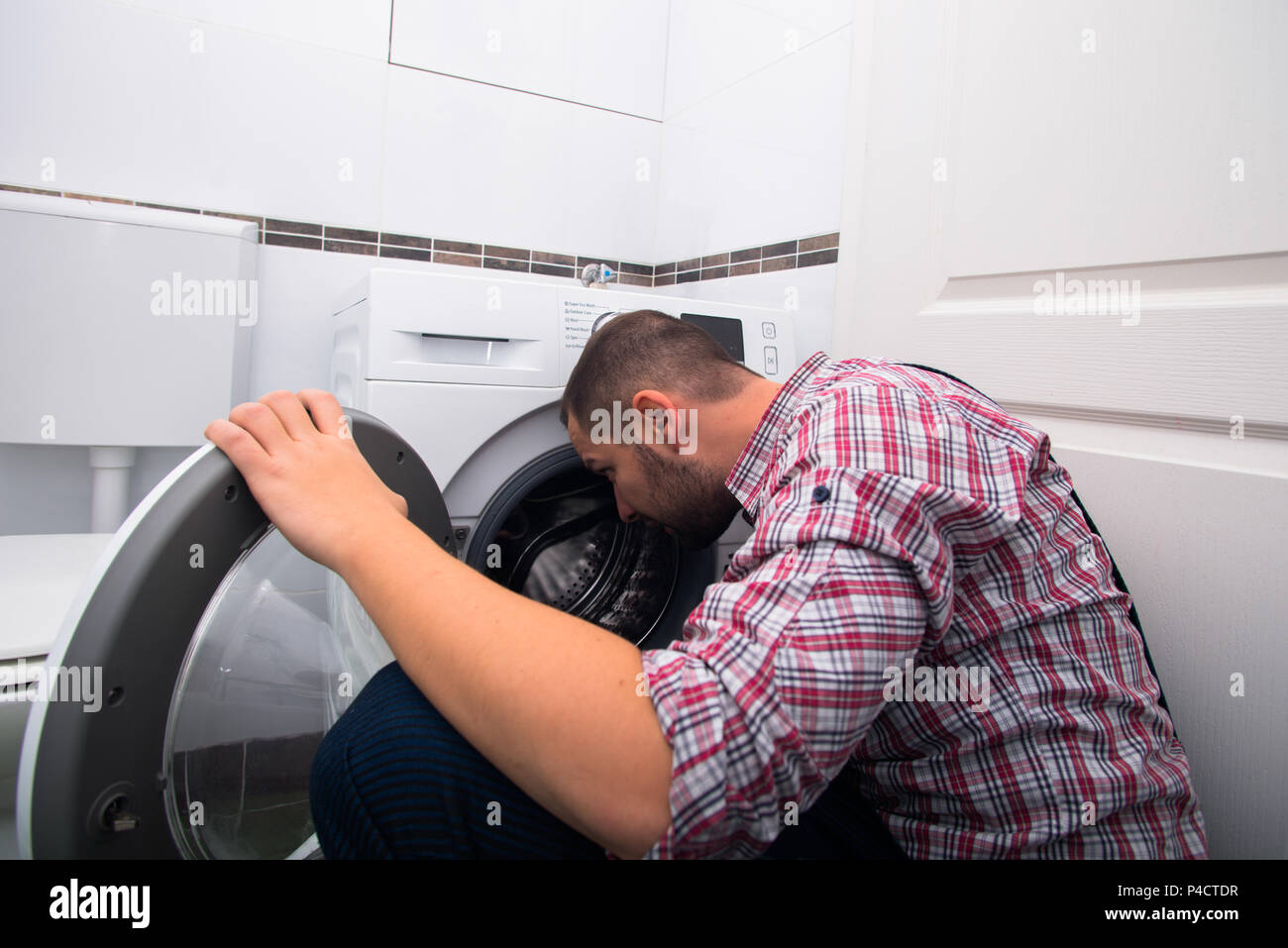 Repair man fixing the washing machine in the bathroom Stock Photo - Alamy