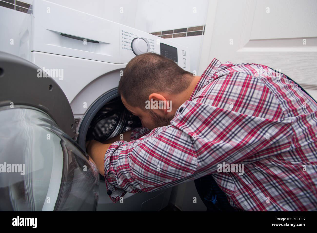 Repair man fixing the washing machine in the bathroom Stock Photo - Alamy