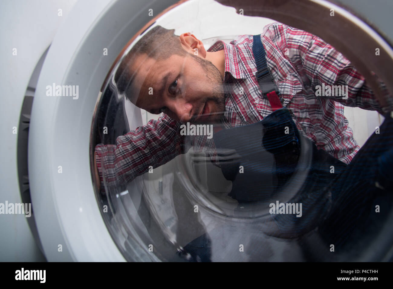 Repair man fixing the washing machine in the bathroom Stock Photo - Alamy