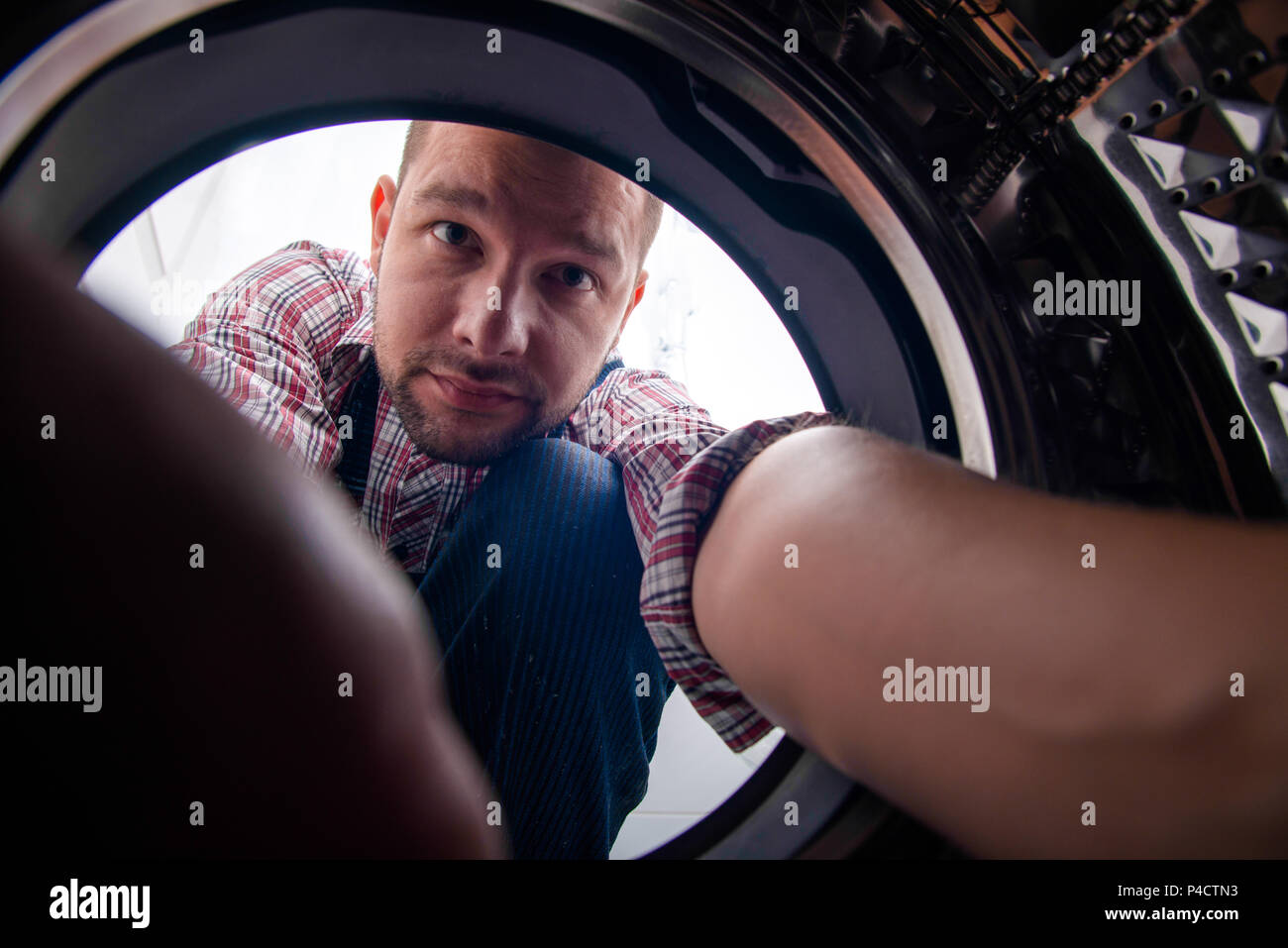 Repair man fixing the washing machine in the bathroom, view from inside ...