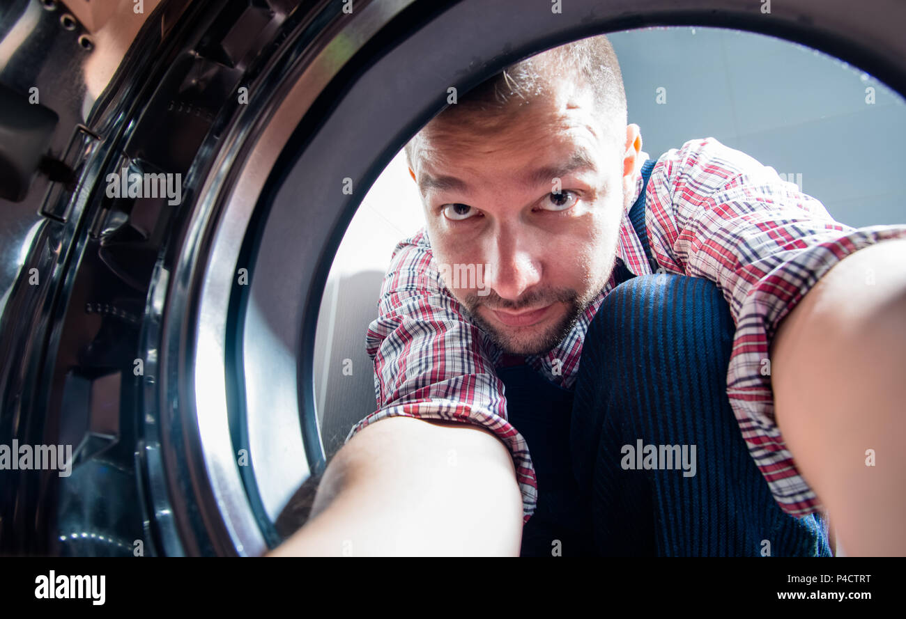 Repair man fixing the washing machine in the bathroom, view from inside ...