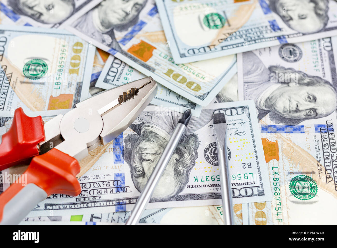 Tools lying over 100 dollars banknotes background. Pliers and ...