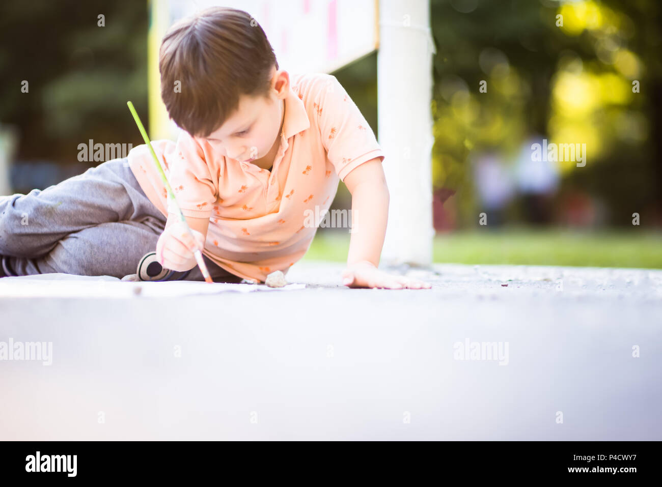 Delightful child lying down and drawing on paper into the park Stock ...
