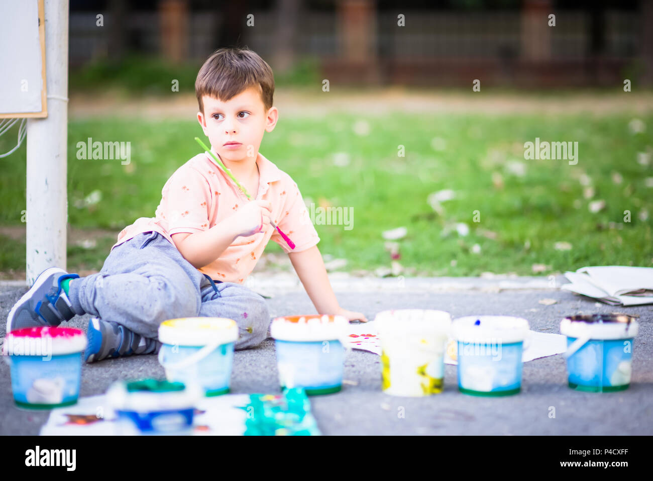Delightful child lying down and drawing on paper into the park Stock ...