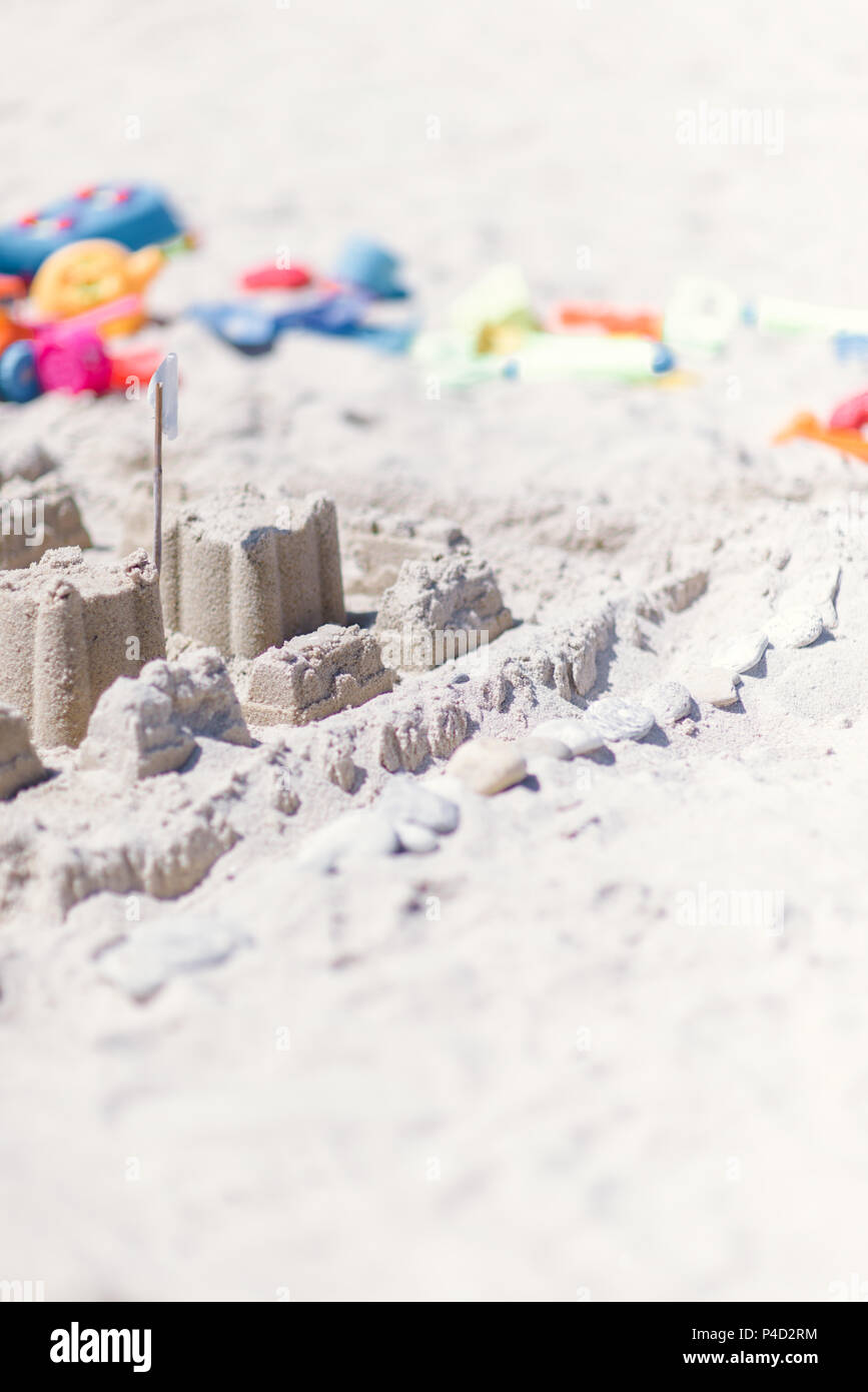 Small but beautiful sand castle on the beach with some toys around and ...