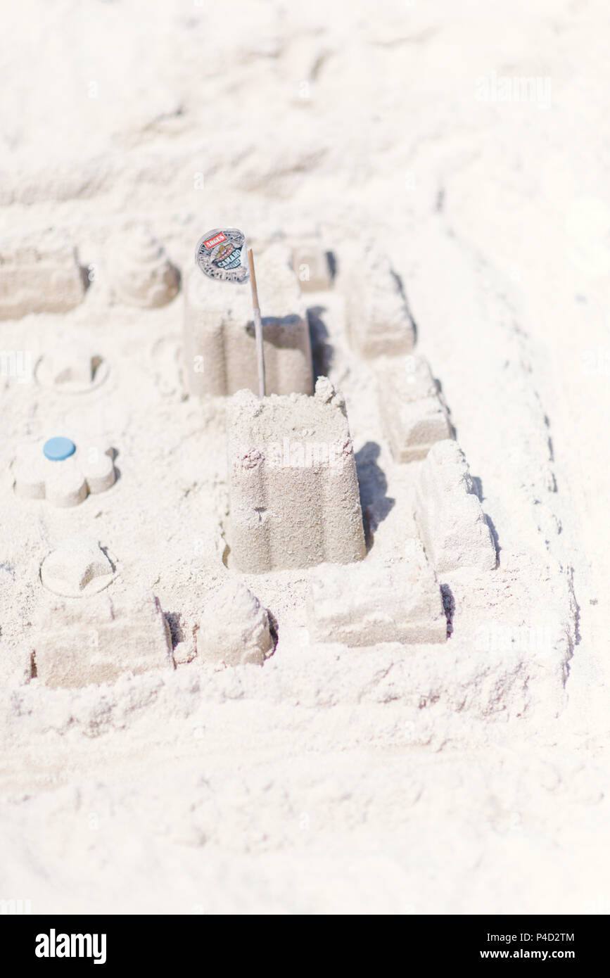 Small but beautiful sand castle on the beach with some toys around and ...