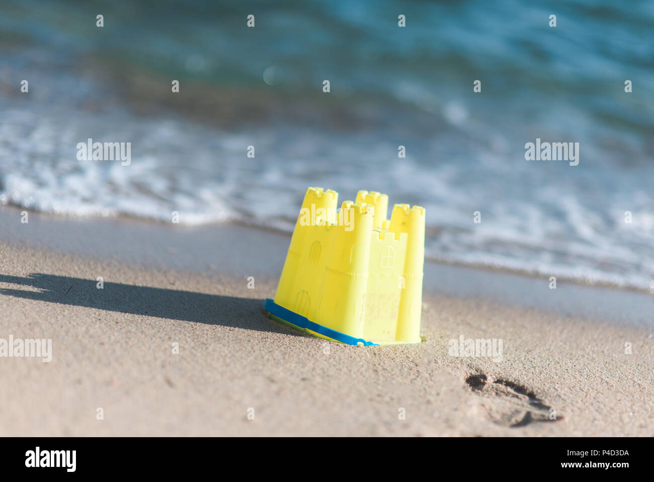 Small but beautiful sand castle on the beach with some toys around and ...
