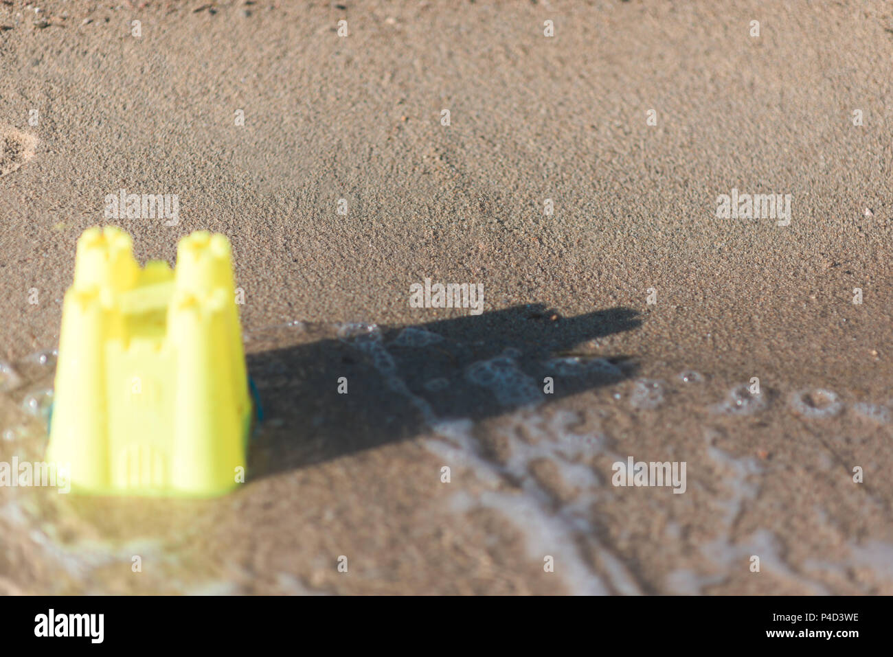 Small but beautiful sand castle on the beach with some toys around and ...