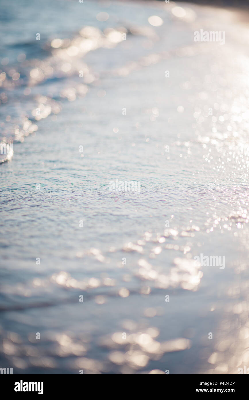 Close up of foamy salt water waves splashing on the golden shores of ...