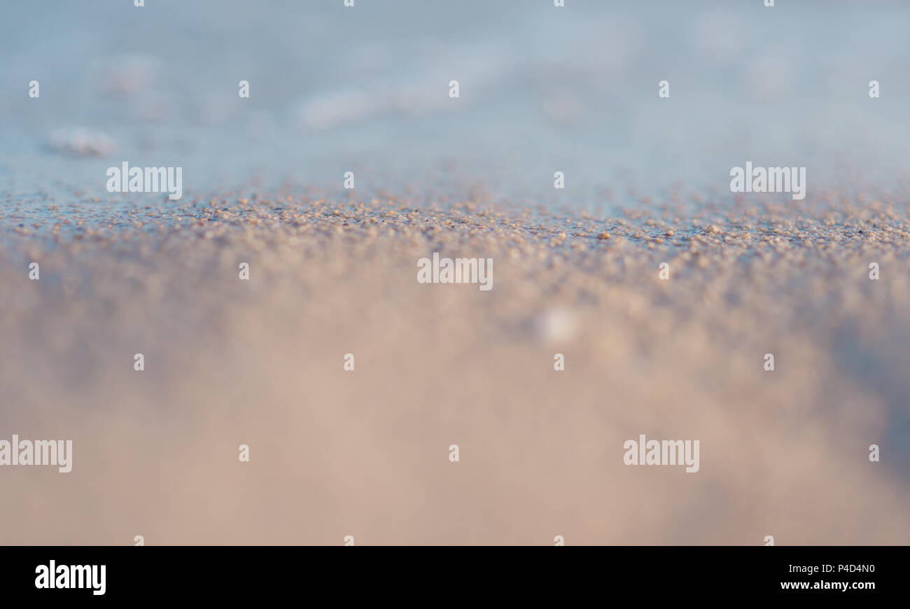 Close up of foamy salt water waves splashing on the golden shores of ...