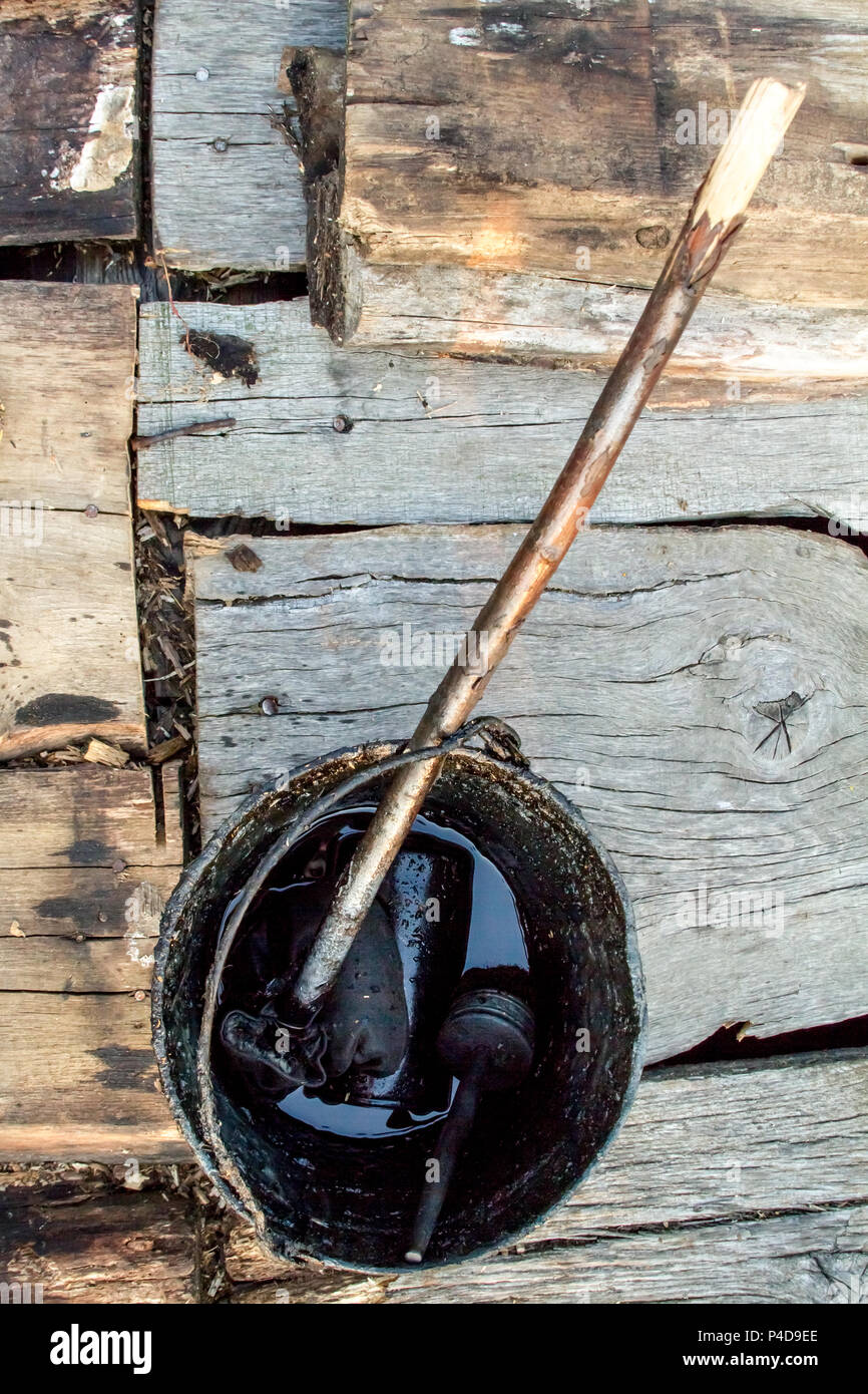 A bucket of black tar boils on the fire for use in repair and ...