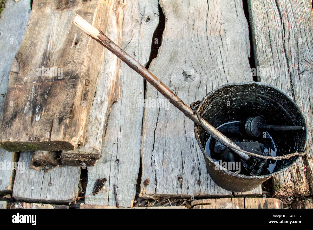 A bucket of black tar boils on the fire for use in repair and ...