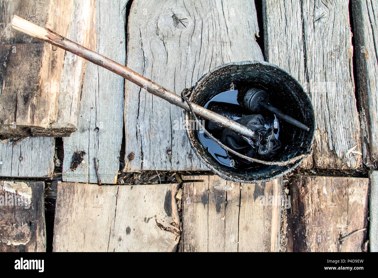 A bucket of black tar boils on the fire for use in repair and ...