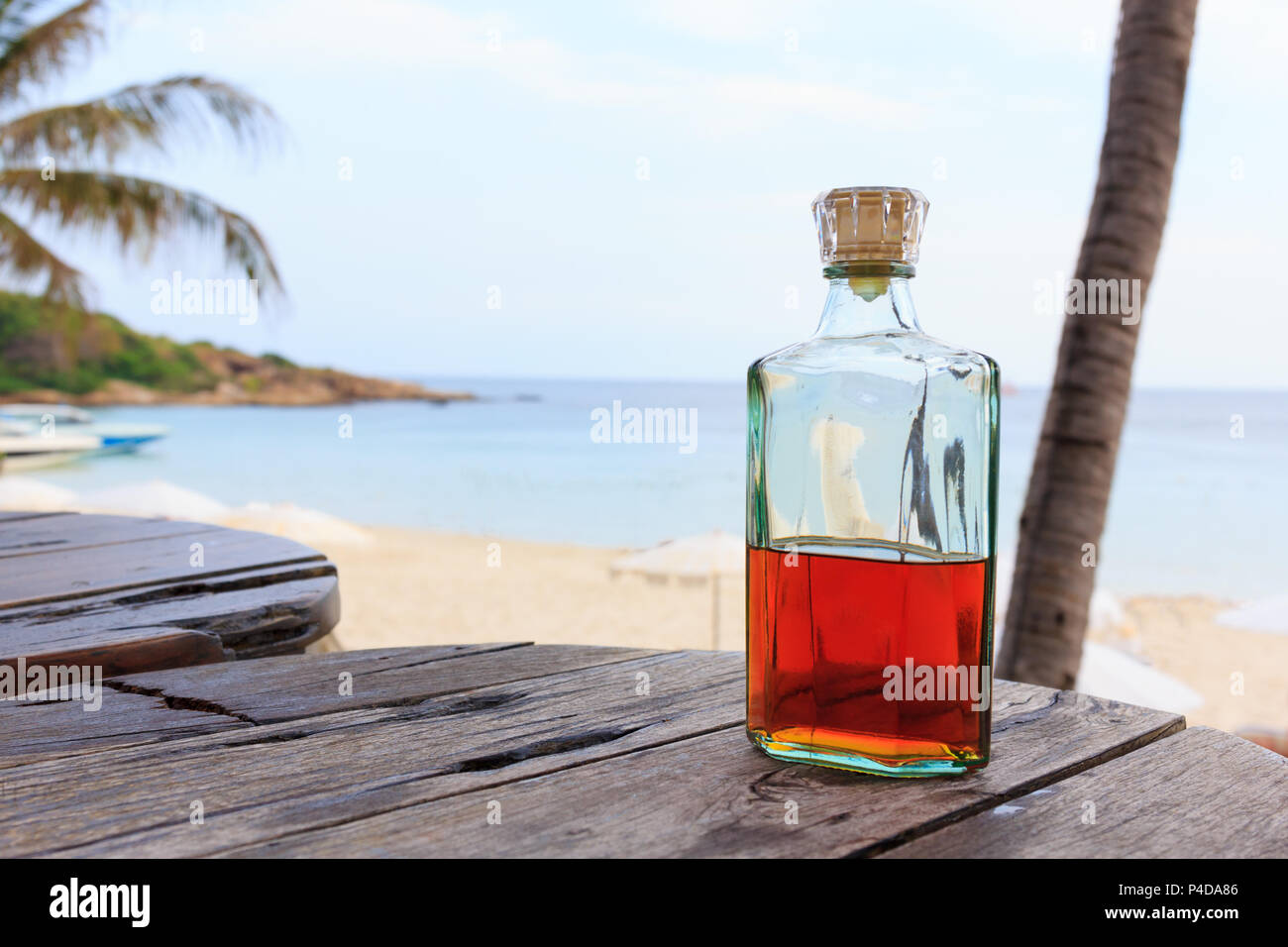 Beverage alcohol is brandy bottle on wood table at sea beach background ...