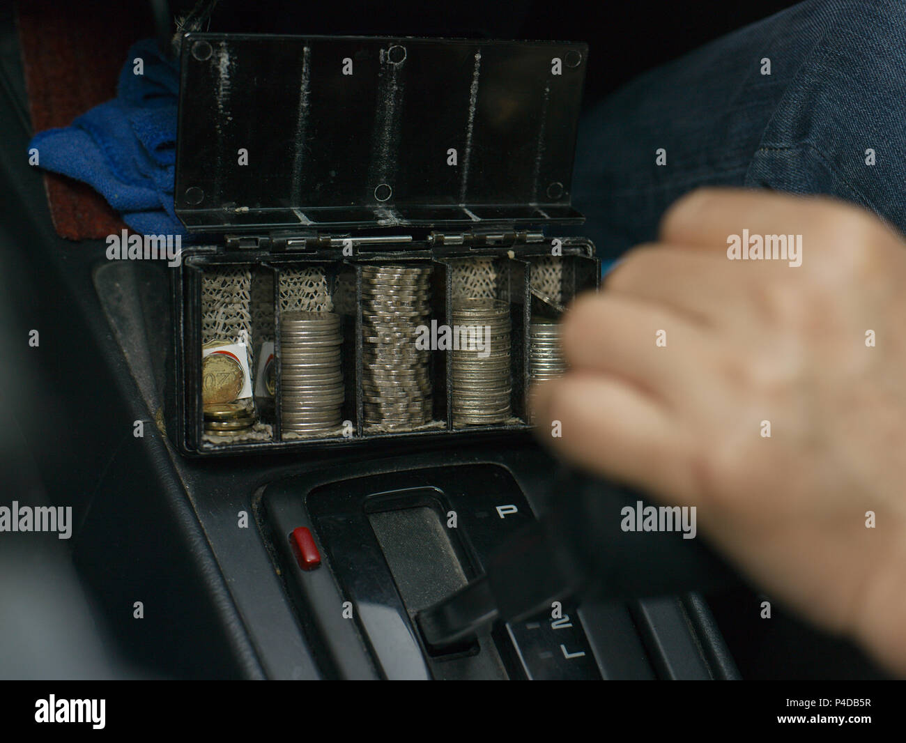 Coins in compartment and a taxi driver hand on gear stick Stock Photo ...
