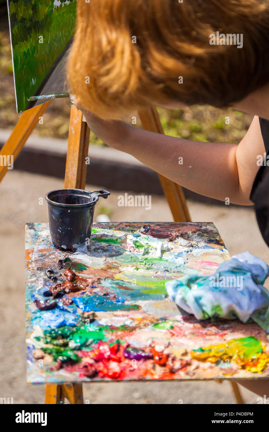 A close-up artist paints on a canvas an urban landscape of a summer ...