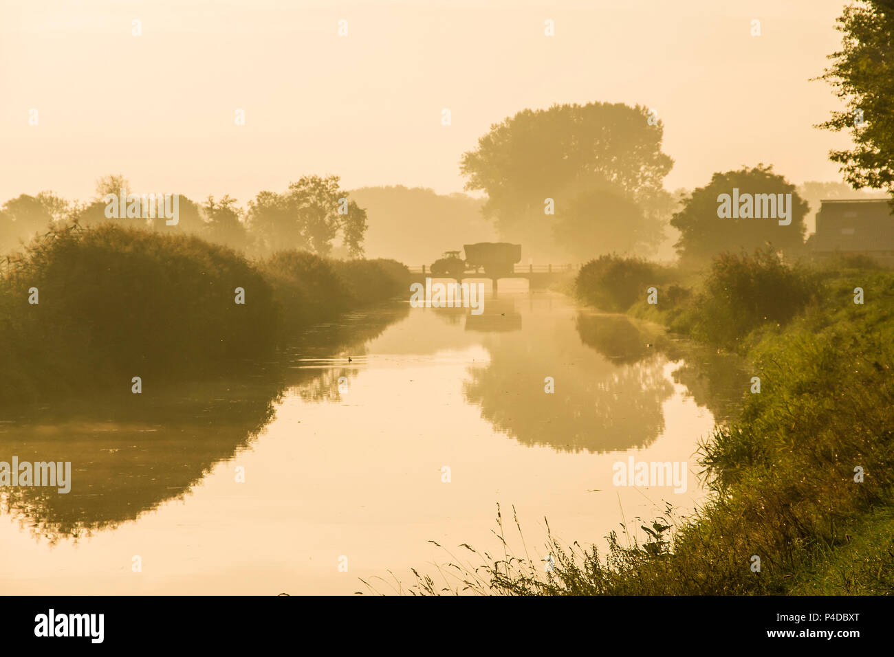 Tractor on a bridge over a river in a hazy morning light Stock Photo ...
