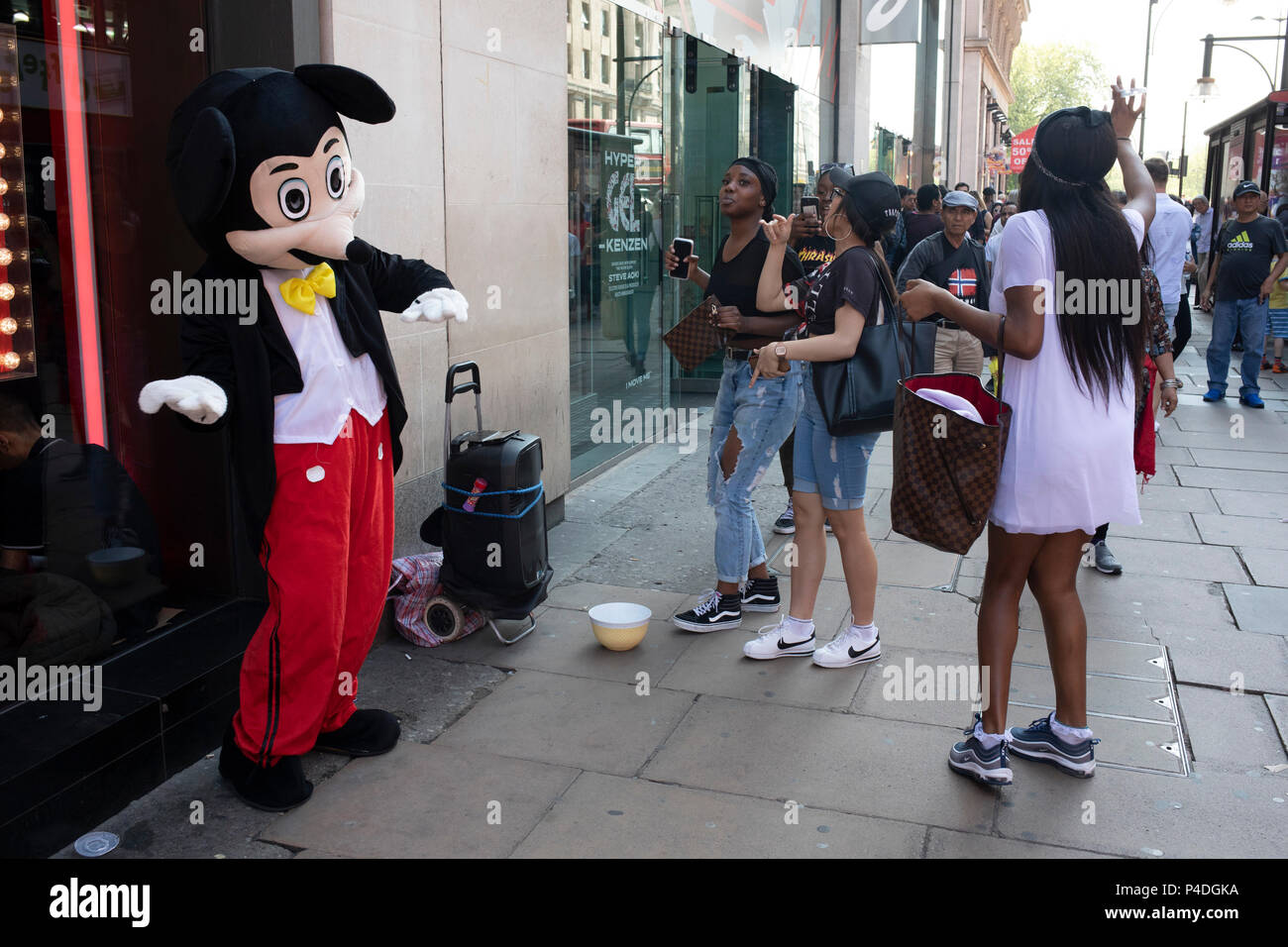 Young women dancing with Mickey Mouse along Oxford Street in London ...