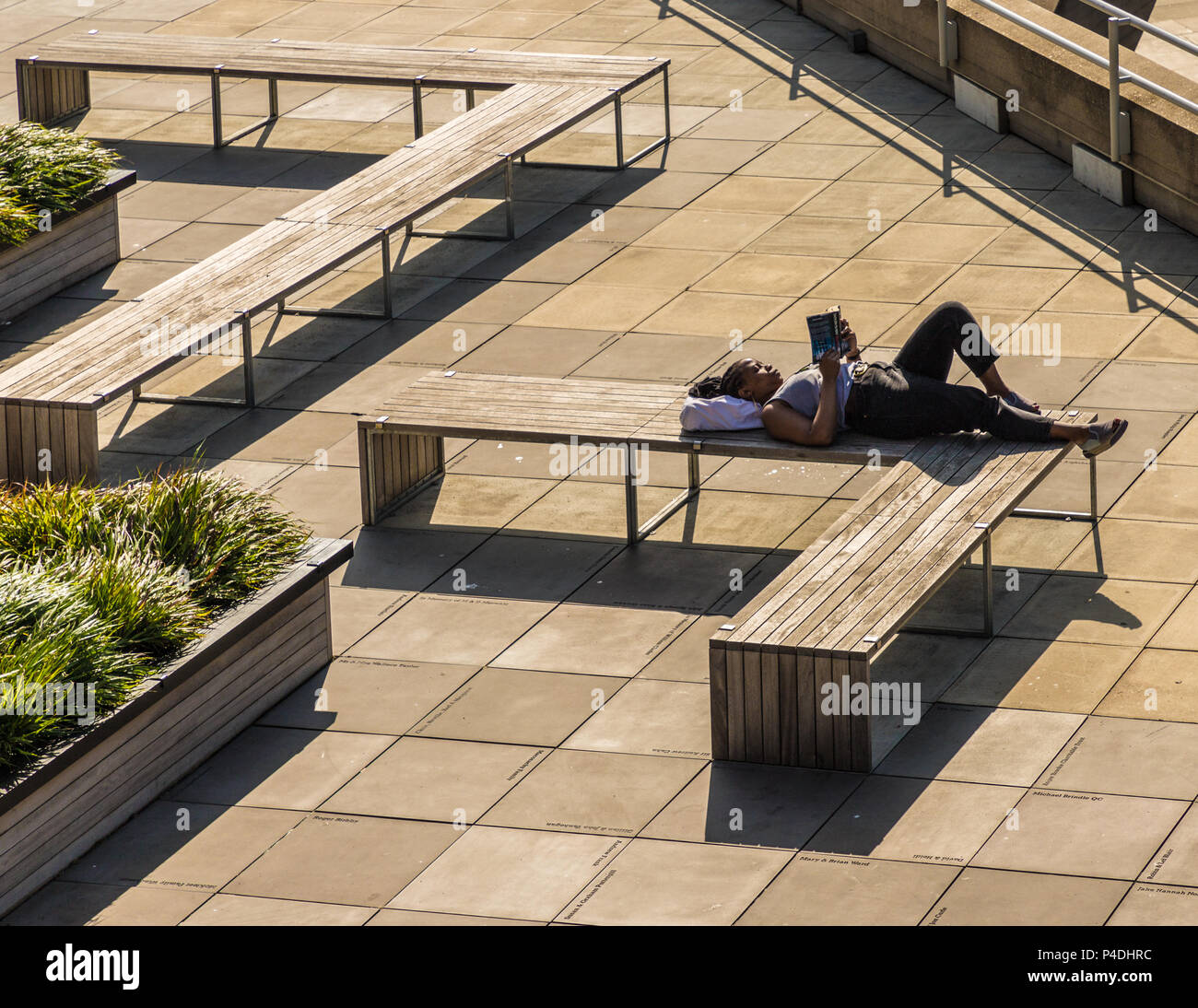 London. June 2018. A view of a female relaxing on modern benches along ...