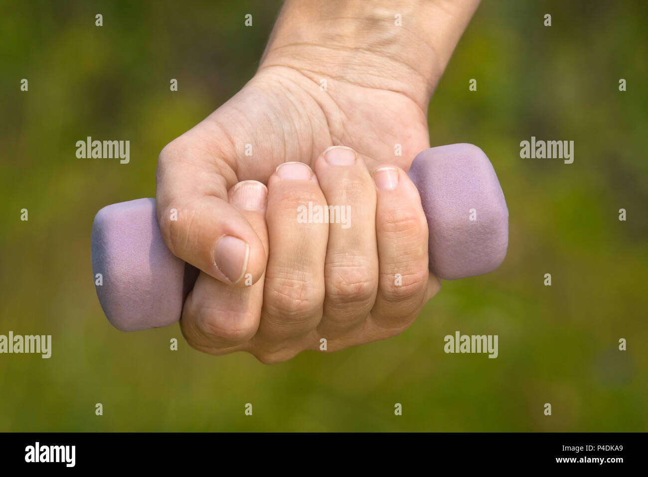 hand holding dumbbell on green blurred background Stock Photo - Alamy