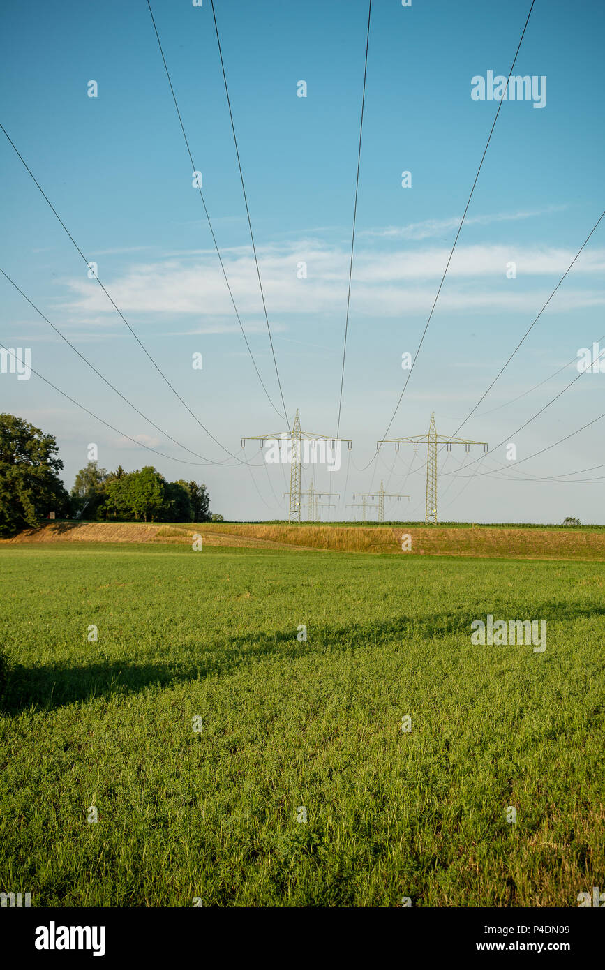 Powerlines cross over a field at sunset Stock Photo - Alamy