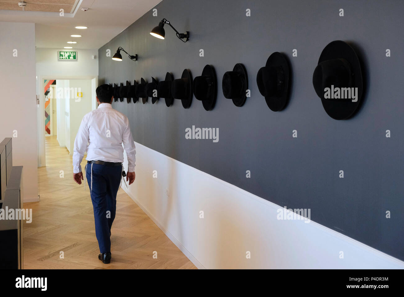 An ultra orthodox Jew walks past traditional Haredi hats hanging on a ...