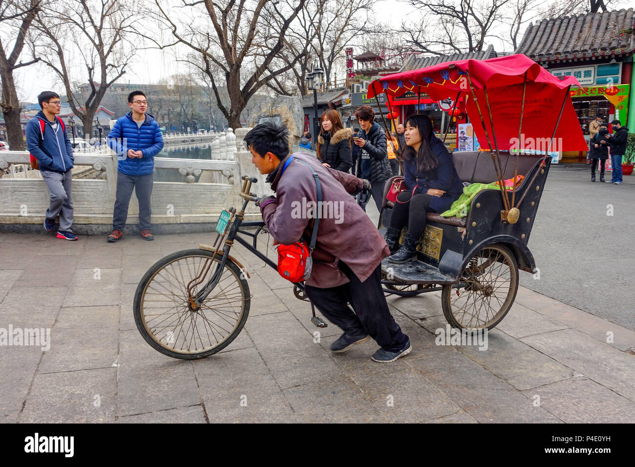 BEIJING, CHINA - MARCH 12, 2016: Tourists in a rickshaw in a hutong ...