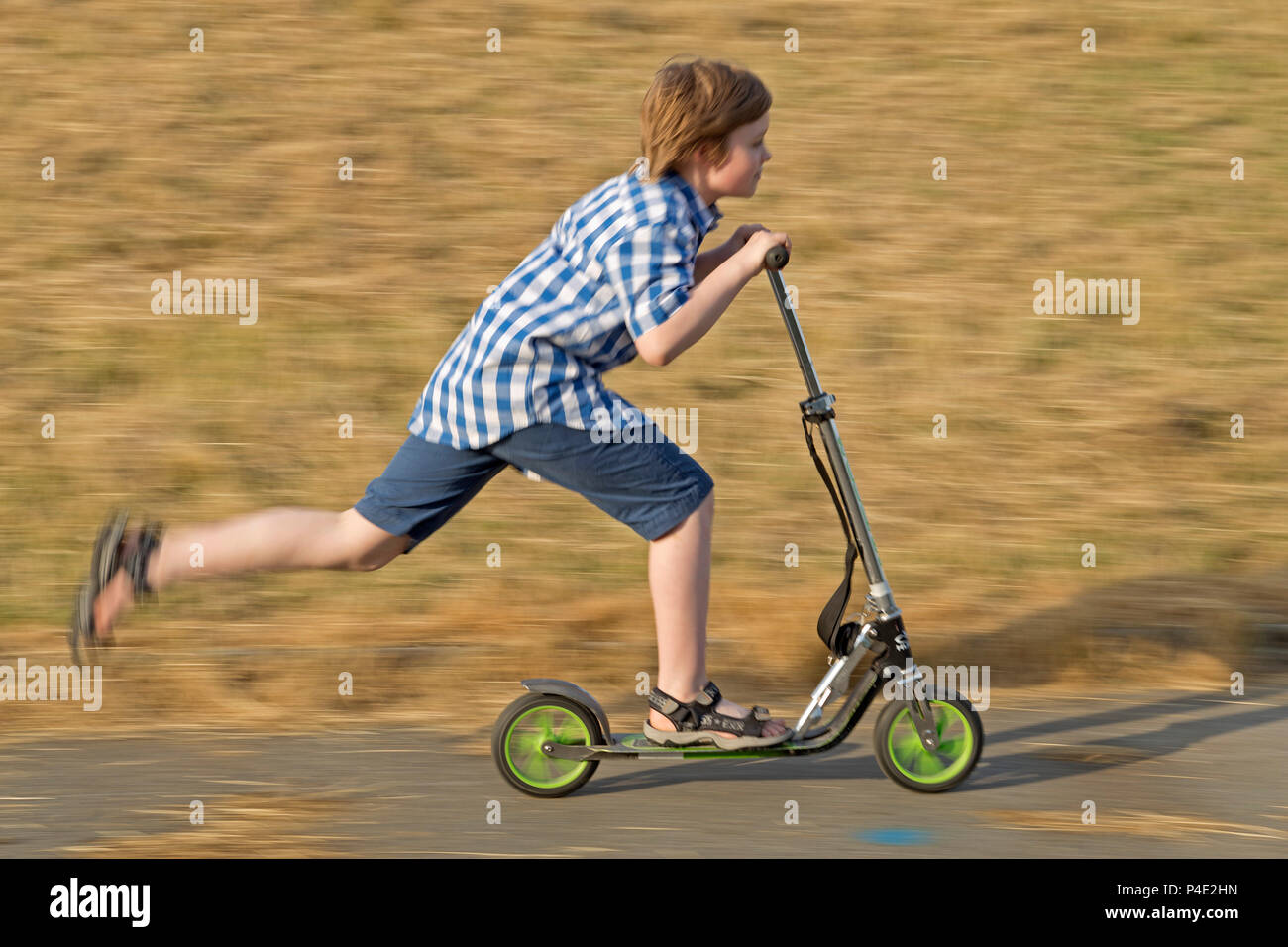 young boy riding his scooter Stock Photo - Alamy