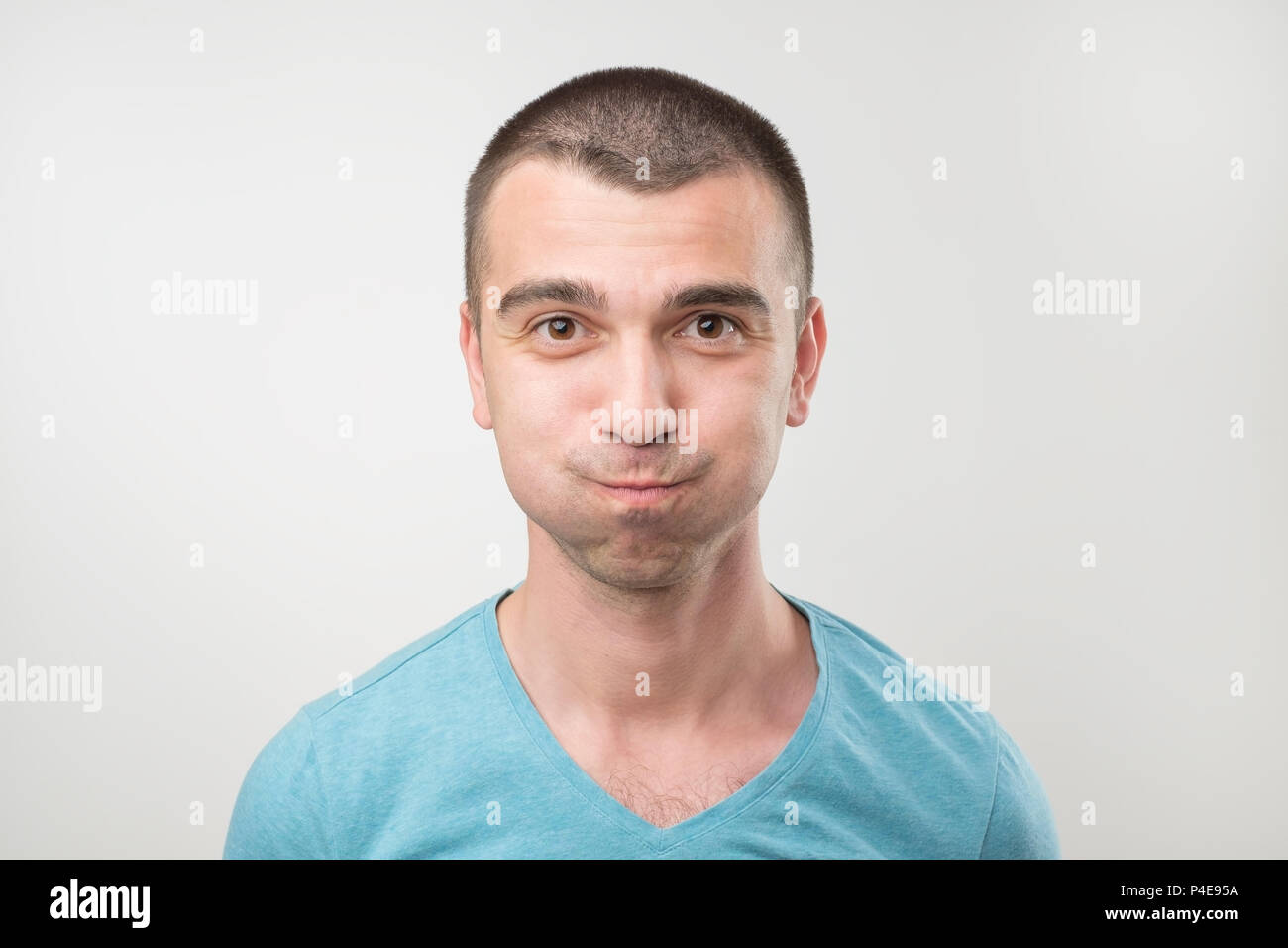 Humorous emotional portrait of grimacing young man. He is blowing his ...