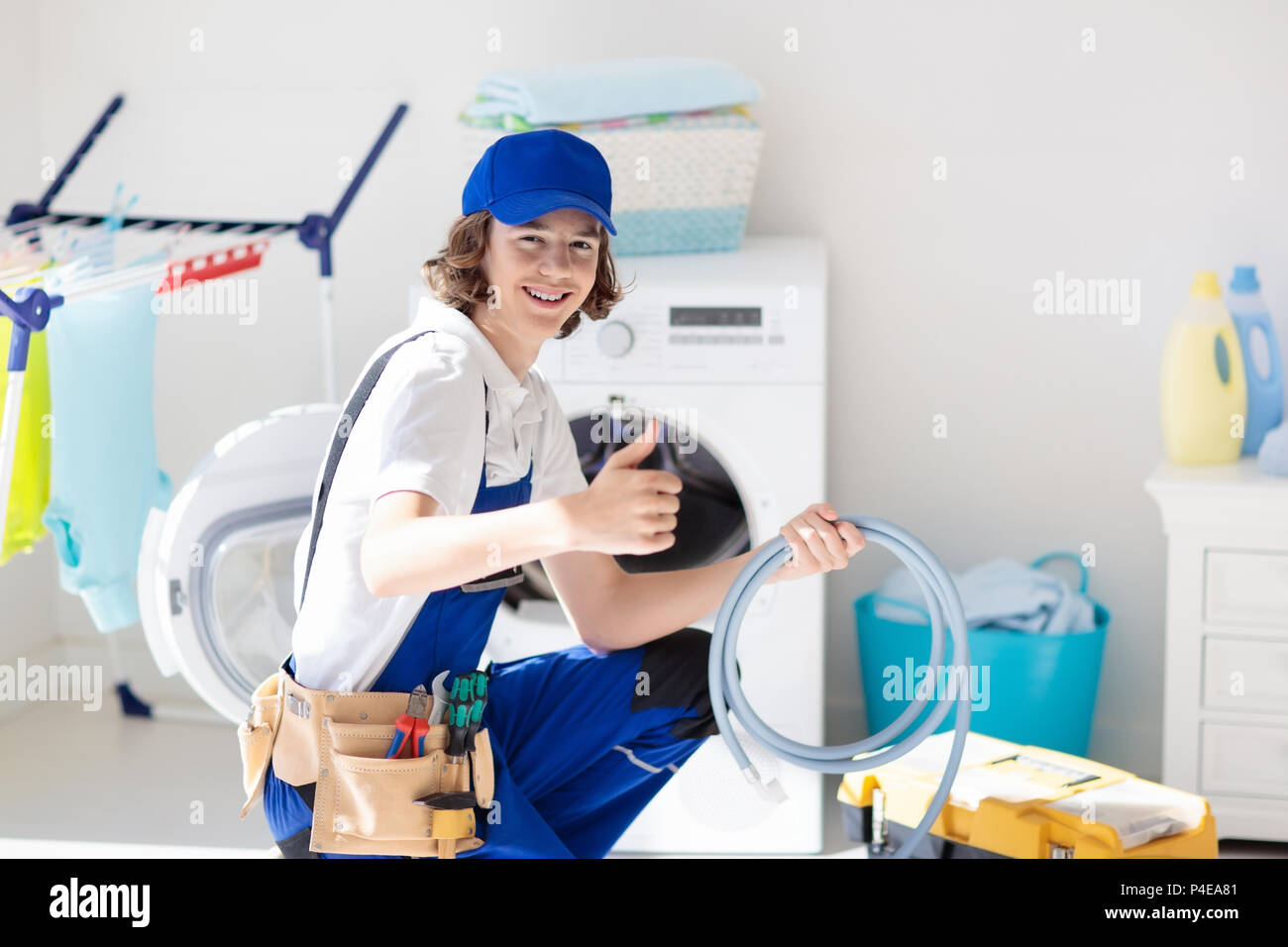 Washing machine repair service. Young male technician in blue uniform ...